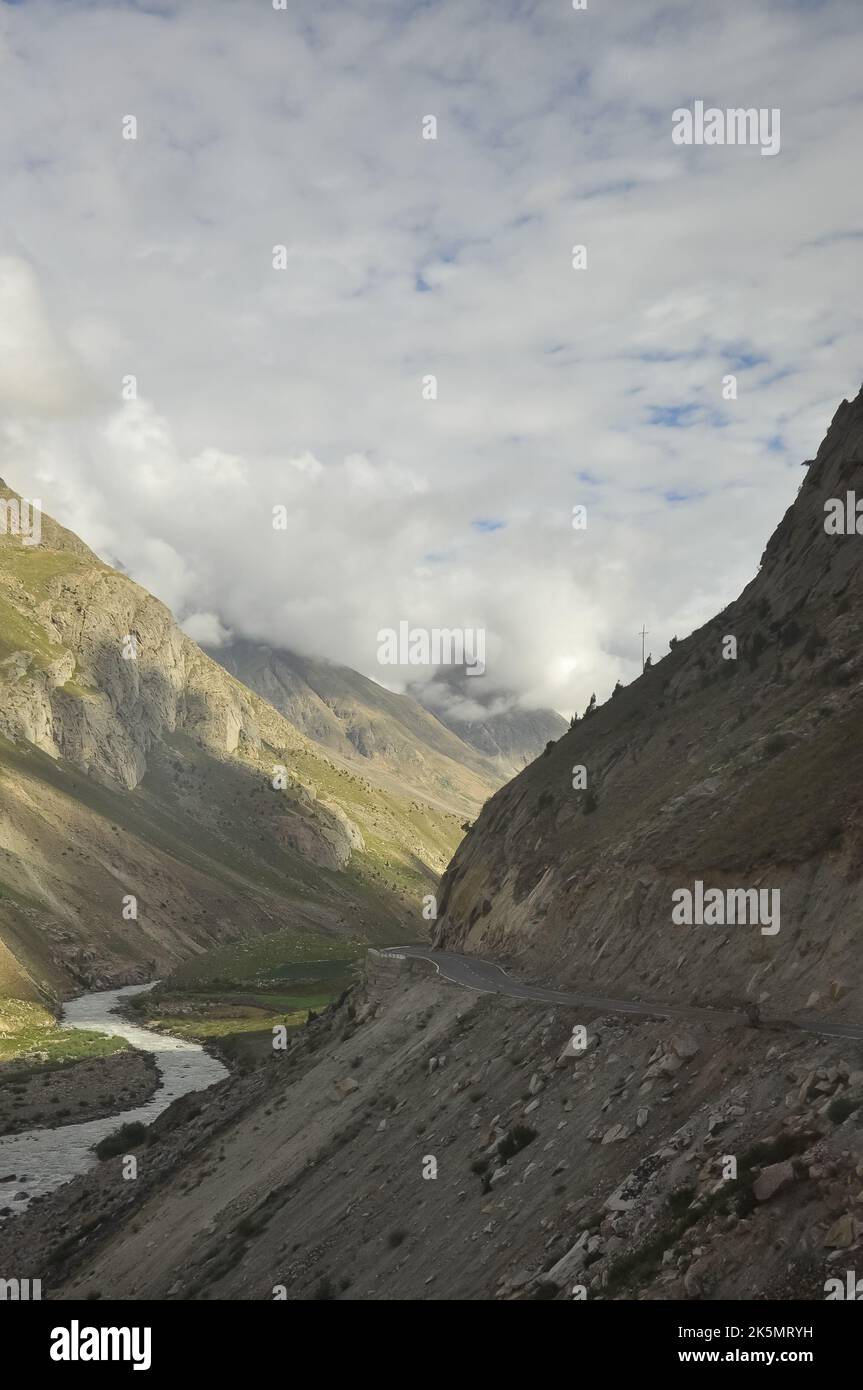 View of narrow cliffside mountain road with flowing a river in between ...
