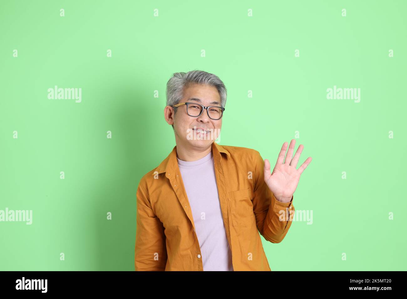 The 40s adult Asian man with yellow shirt standing on the green ...