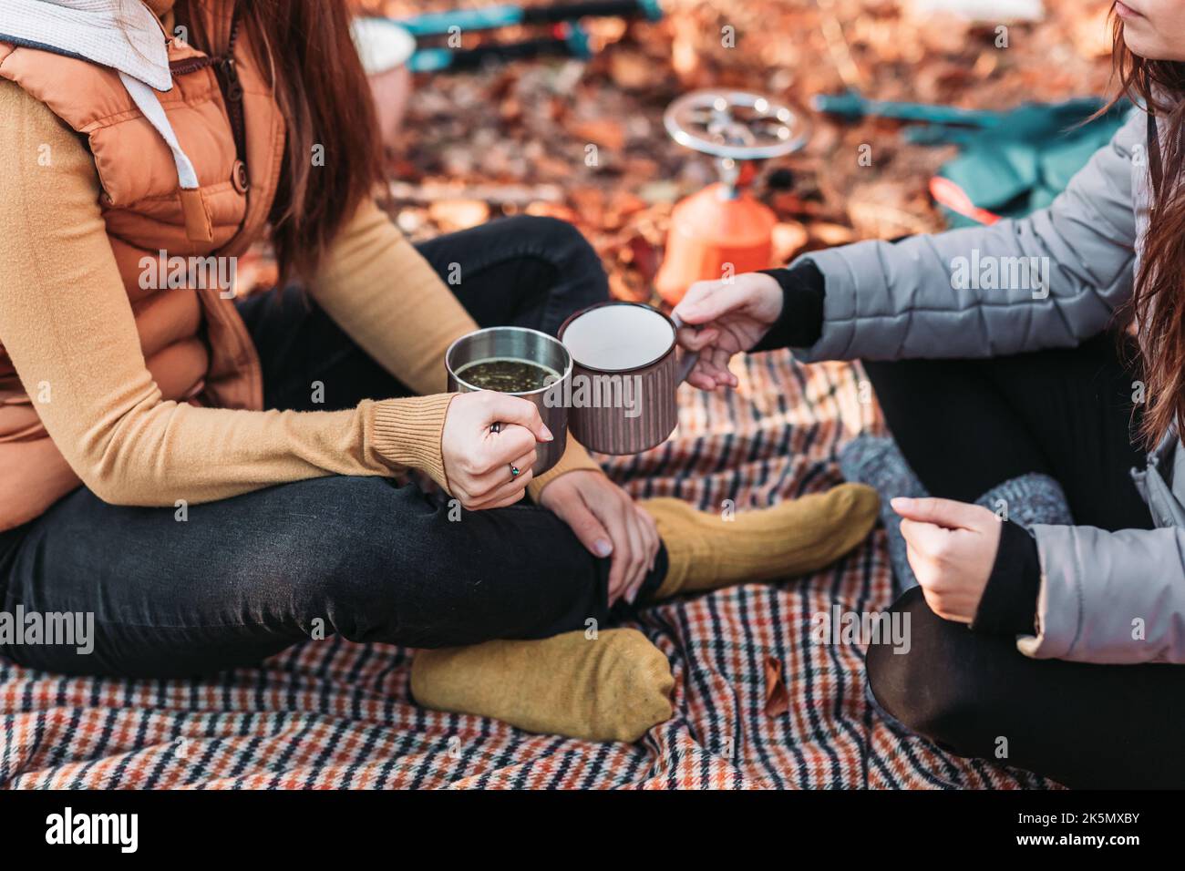 Two girls drinking hot tea from metal cups outdoor, camping Stock Photo ...