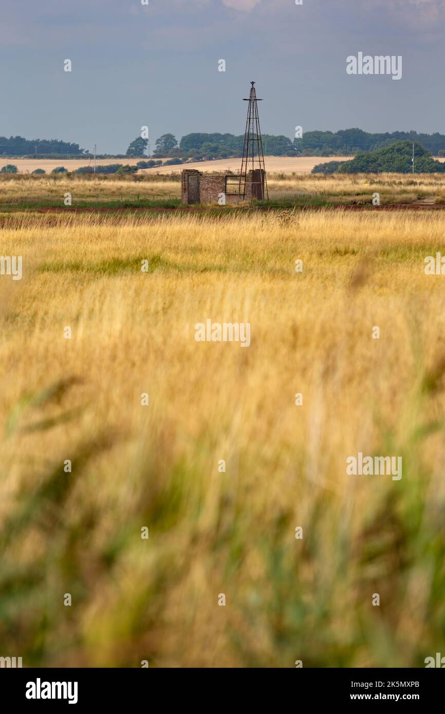 Remnants of hut and mast in a grass and salt marsh landscape, airfield ...