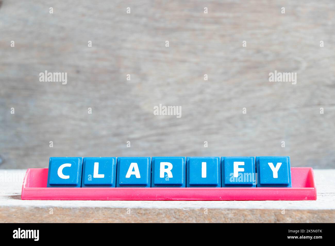 Tile alphabet letter with word clarify in red color rack on wood ...