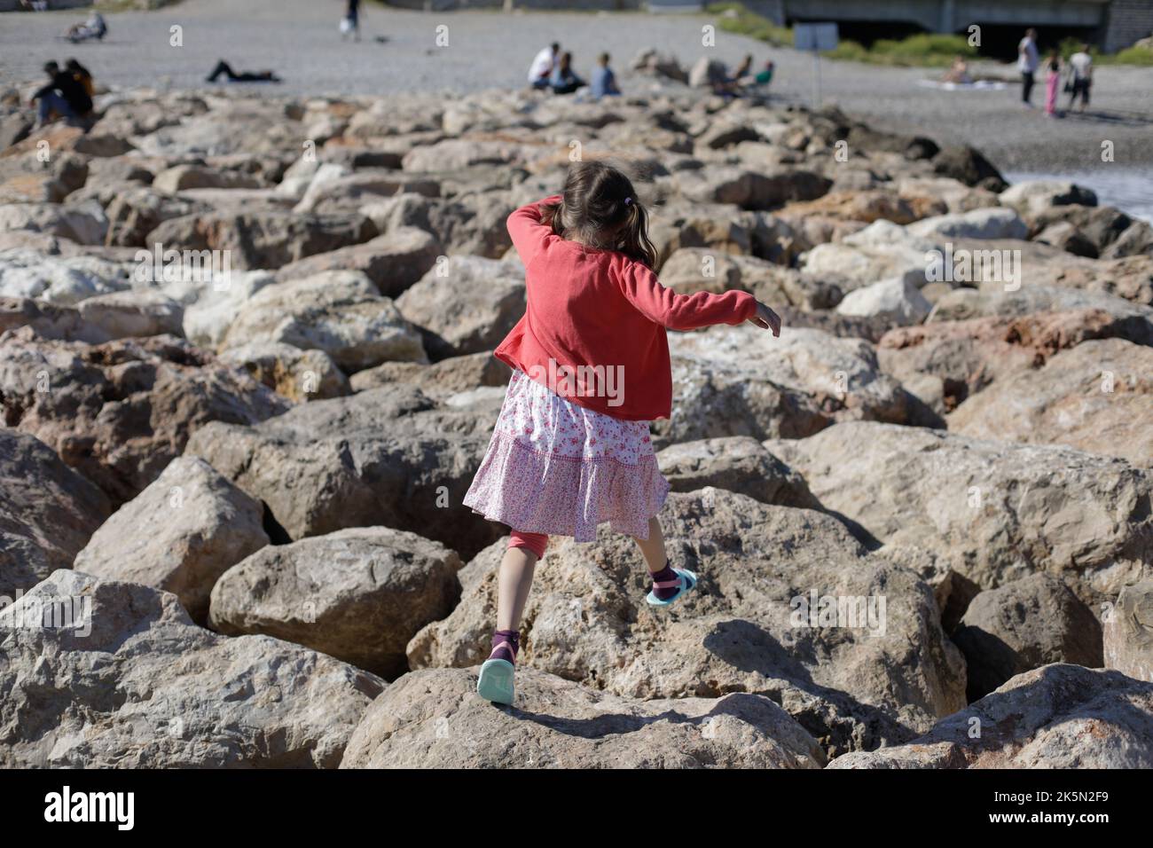 Little girl jumping on rocks on the French riviera during a sunny ...