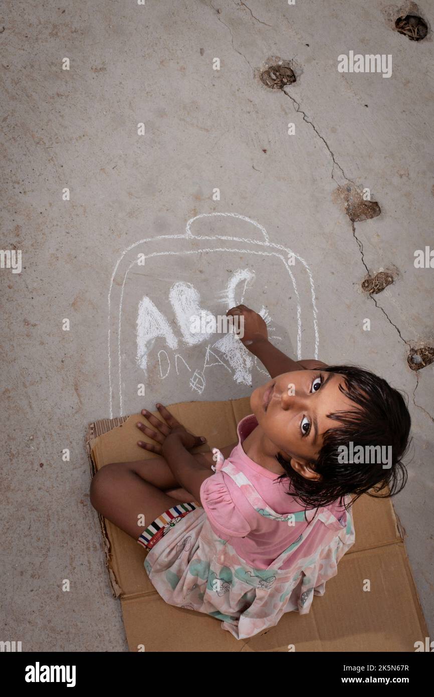 poor indian girl studying and writing on road with chalk in absence of ...