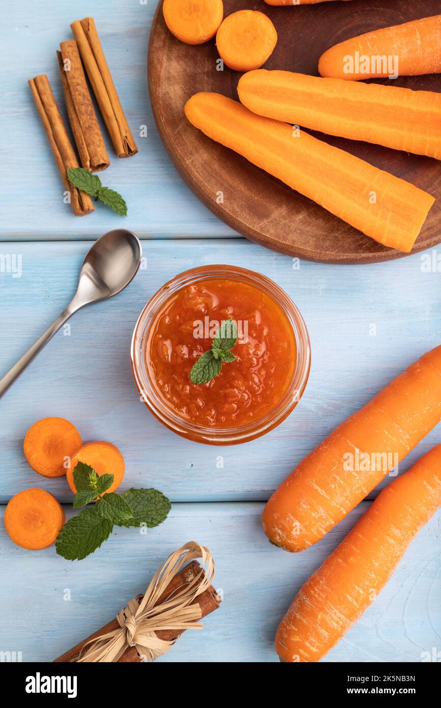 Carrot jam with cinnamon in glass jar on blue wooden background. Top ...