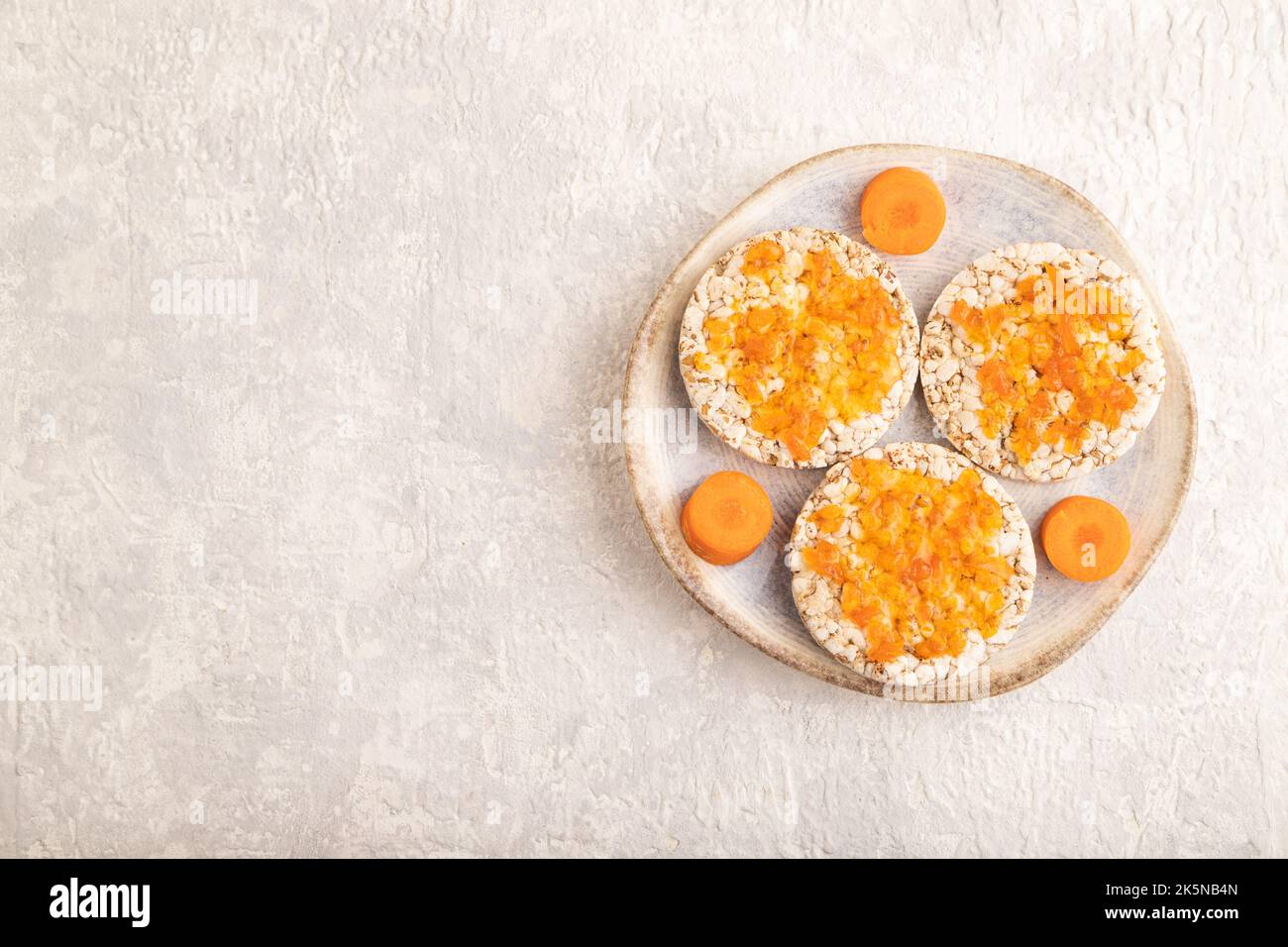 Carrot jam with puffed rice cakes on gray concrete background. Top view ...