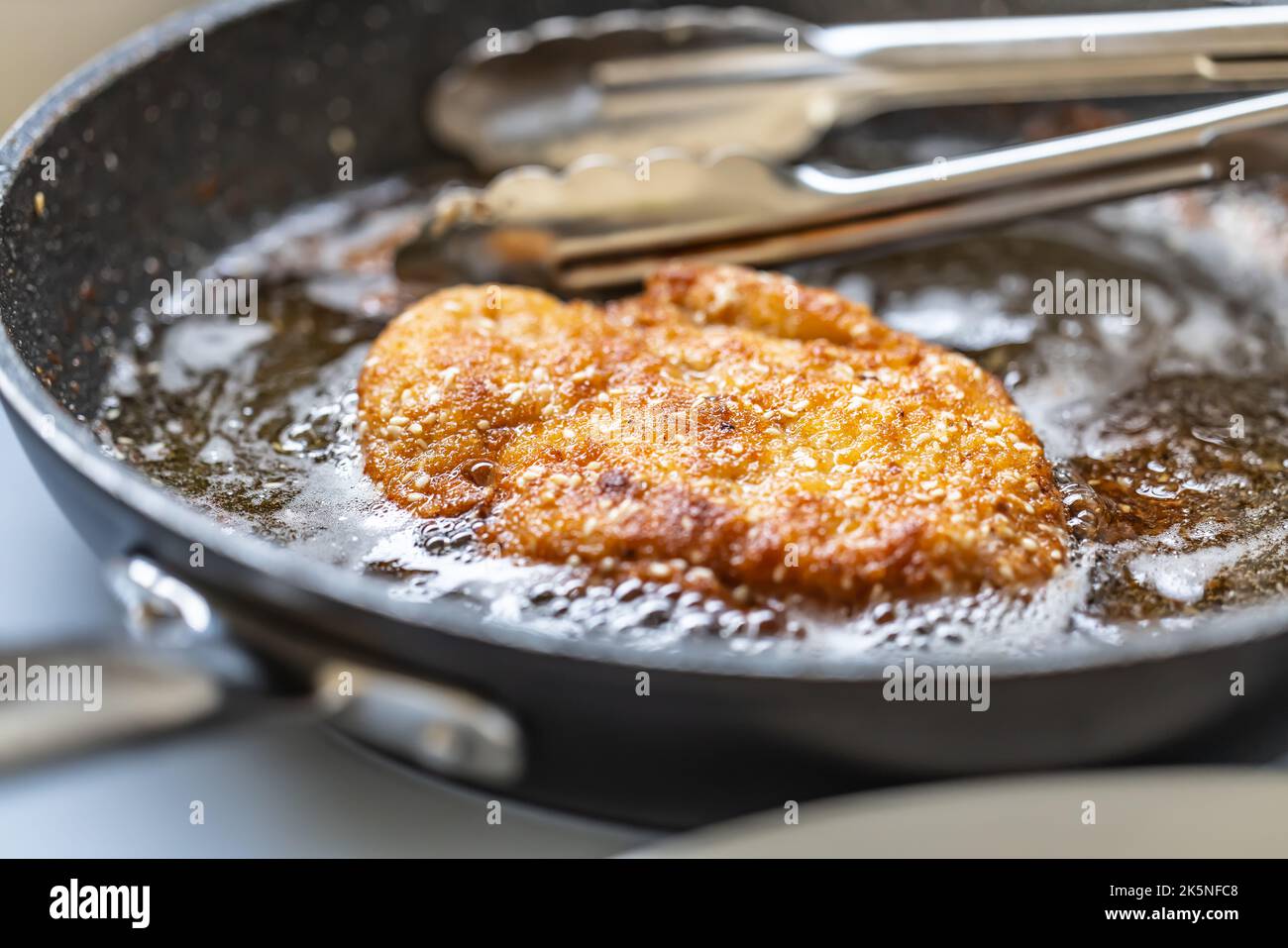 Schnitzel frying in a hot pan finished to golden crispy skin Stock ...