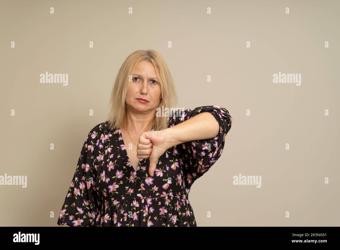 Woman giving thumb down gesture looking with negative expression and ...