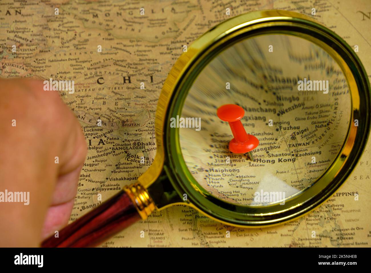 Magnifying glass lying on map next to China and Hong Kong and button ...