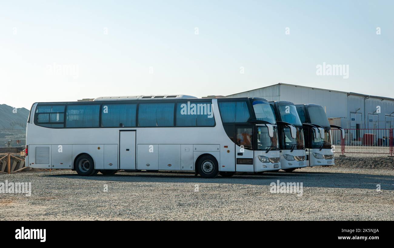 A row of luxury buses parked on the construction site for transporting ...