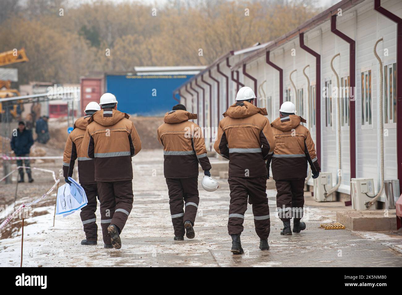 A back view of industrial construction workers wearing uniform on a ...