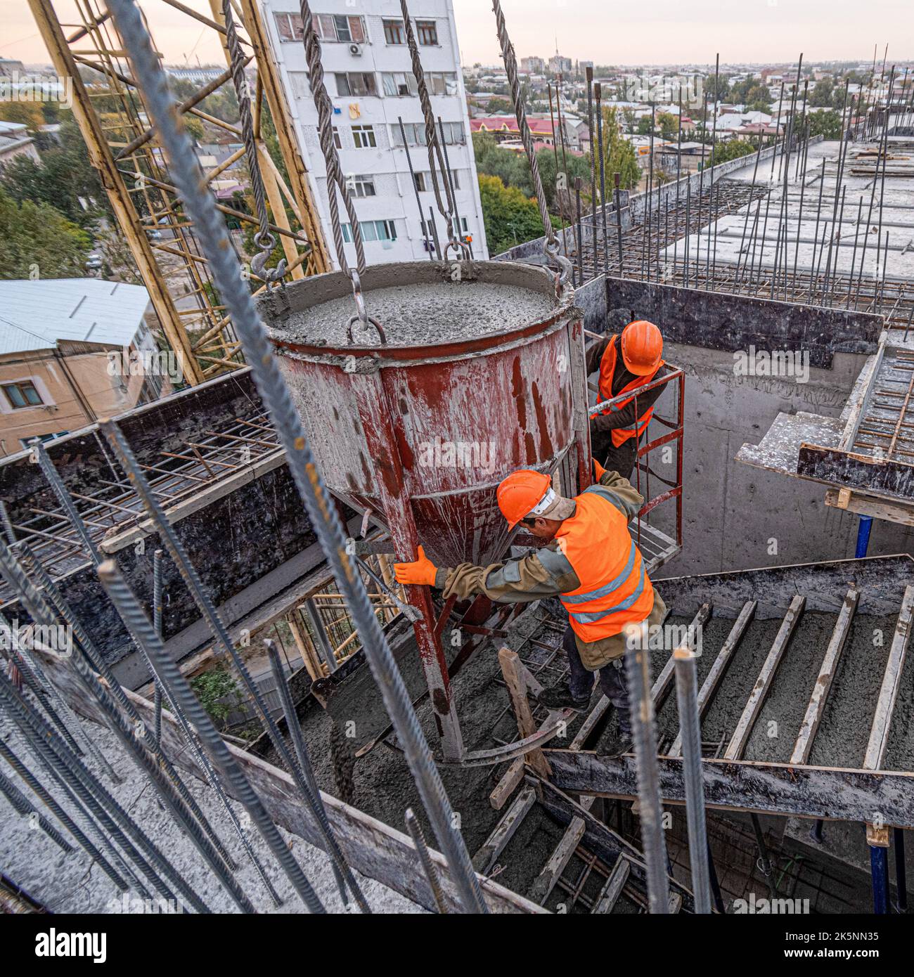 A high-angle shot of men working on the concrete pouring bucket in the ...