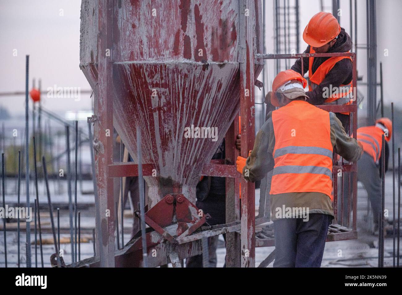 A shot of men working on the concrete pouring bucket in the industrial ...