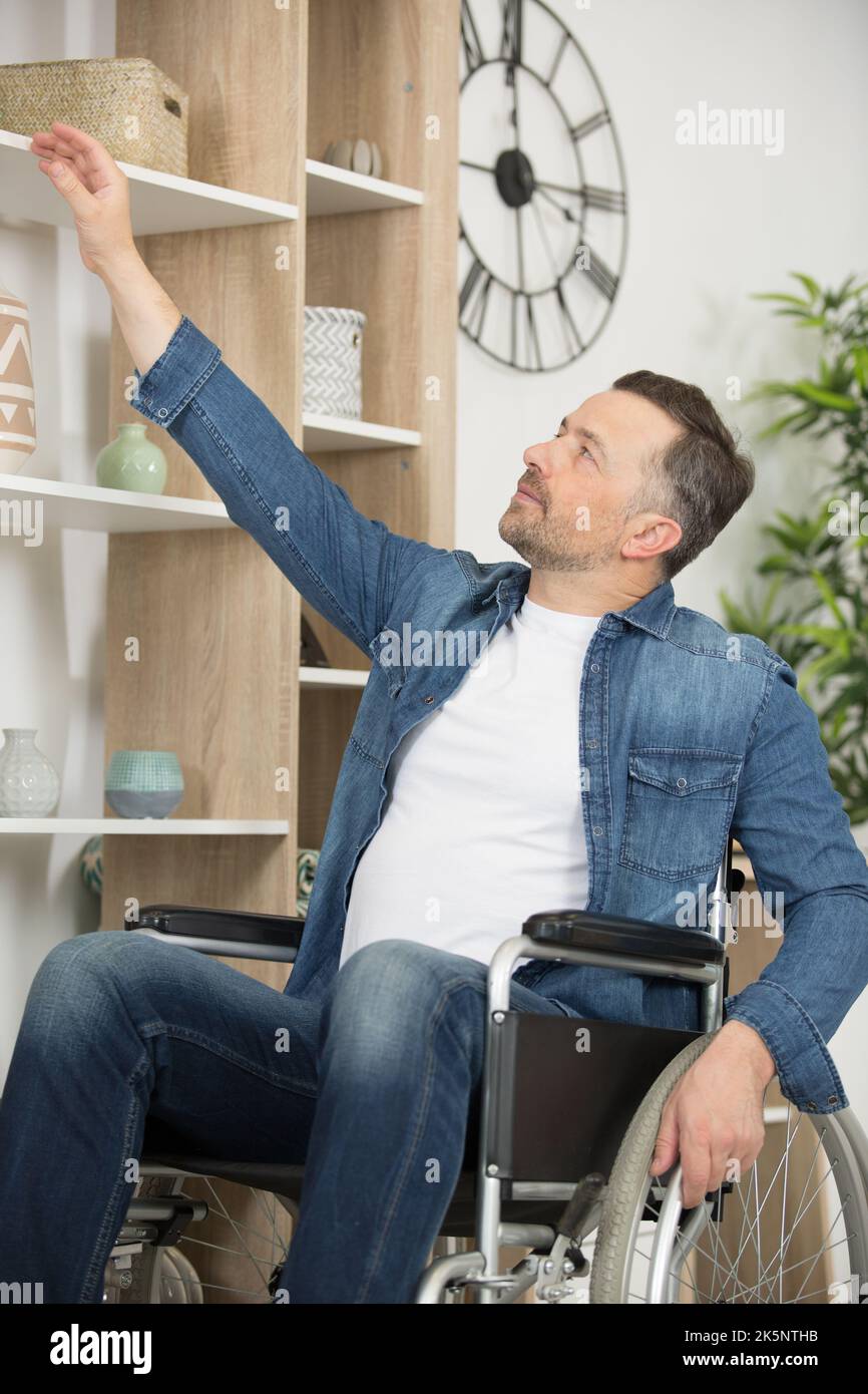 man on wheelchair reaching for something on the shelf Stock Photo - Alamy