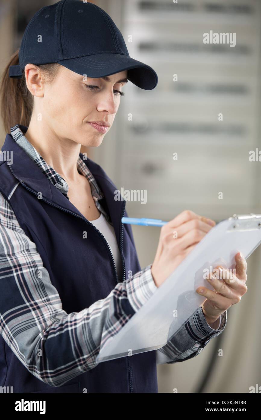 female contractor writing on clipboard Stock Photo - Alamy