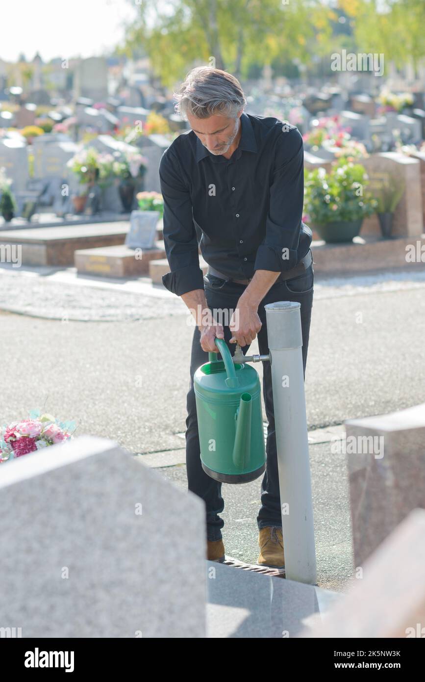 Man collecting water in cemetery Stock Photo - Alamy