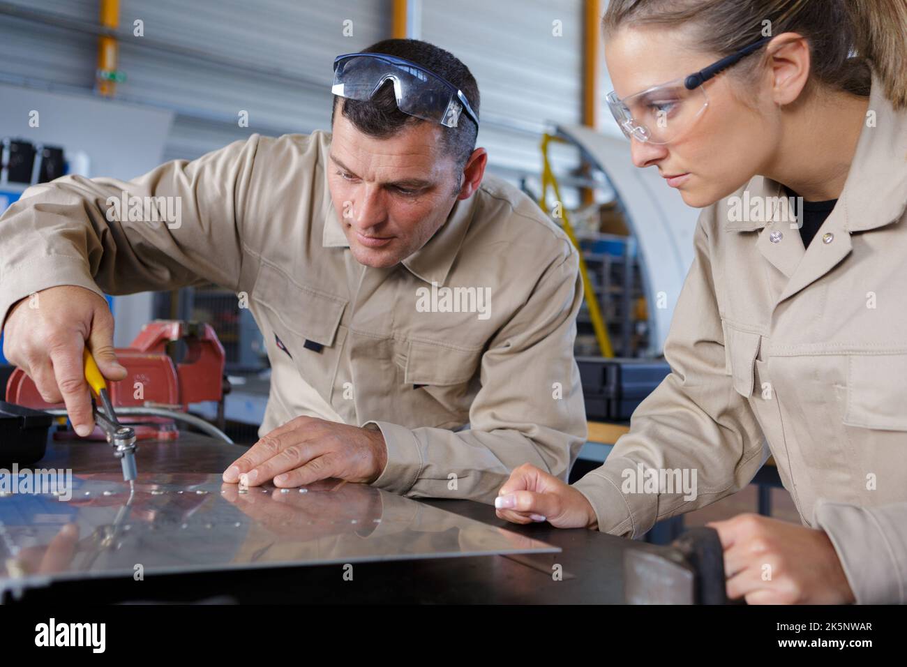 male and female engineers inspecting metal part Stock Photo - Alamy