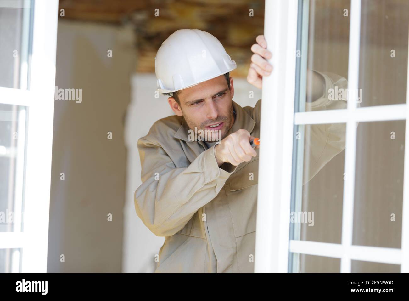 service man installing window with screwdriver Stock Photo - Alamy