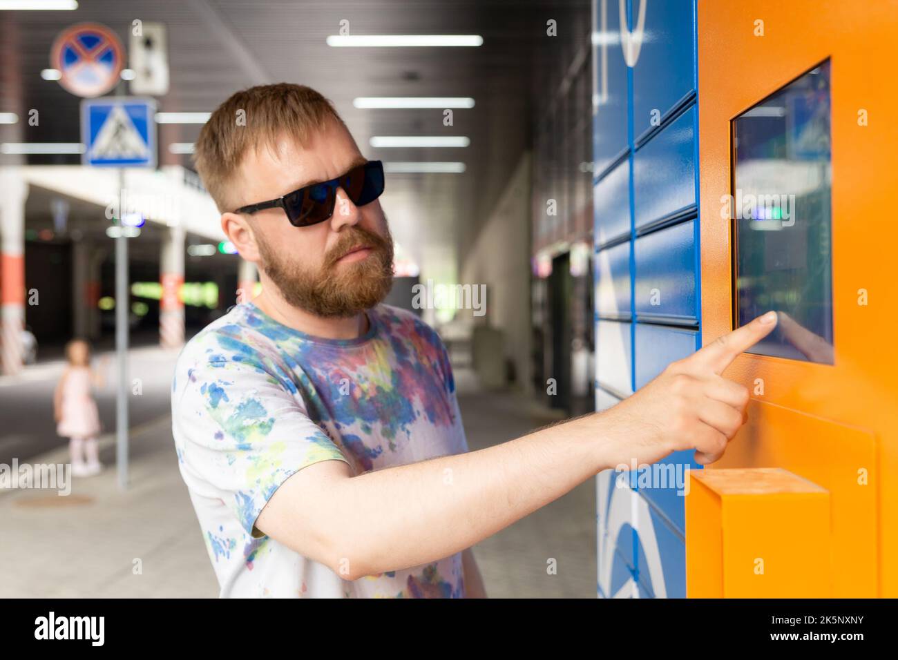 Man enters parcel code on screen and picks up parcel from automated ...