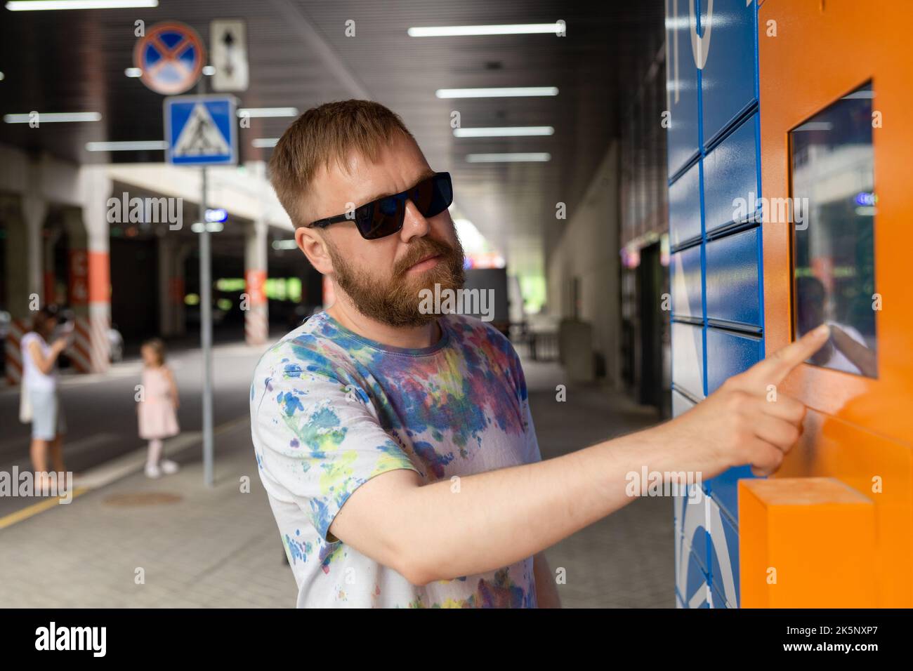 Man enters parcel code on screen and picks up parcel from automated ...