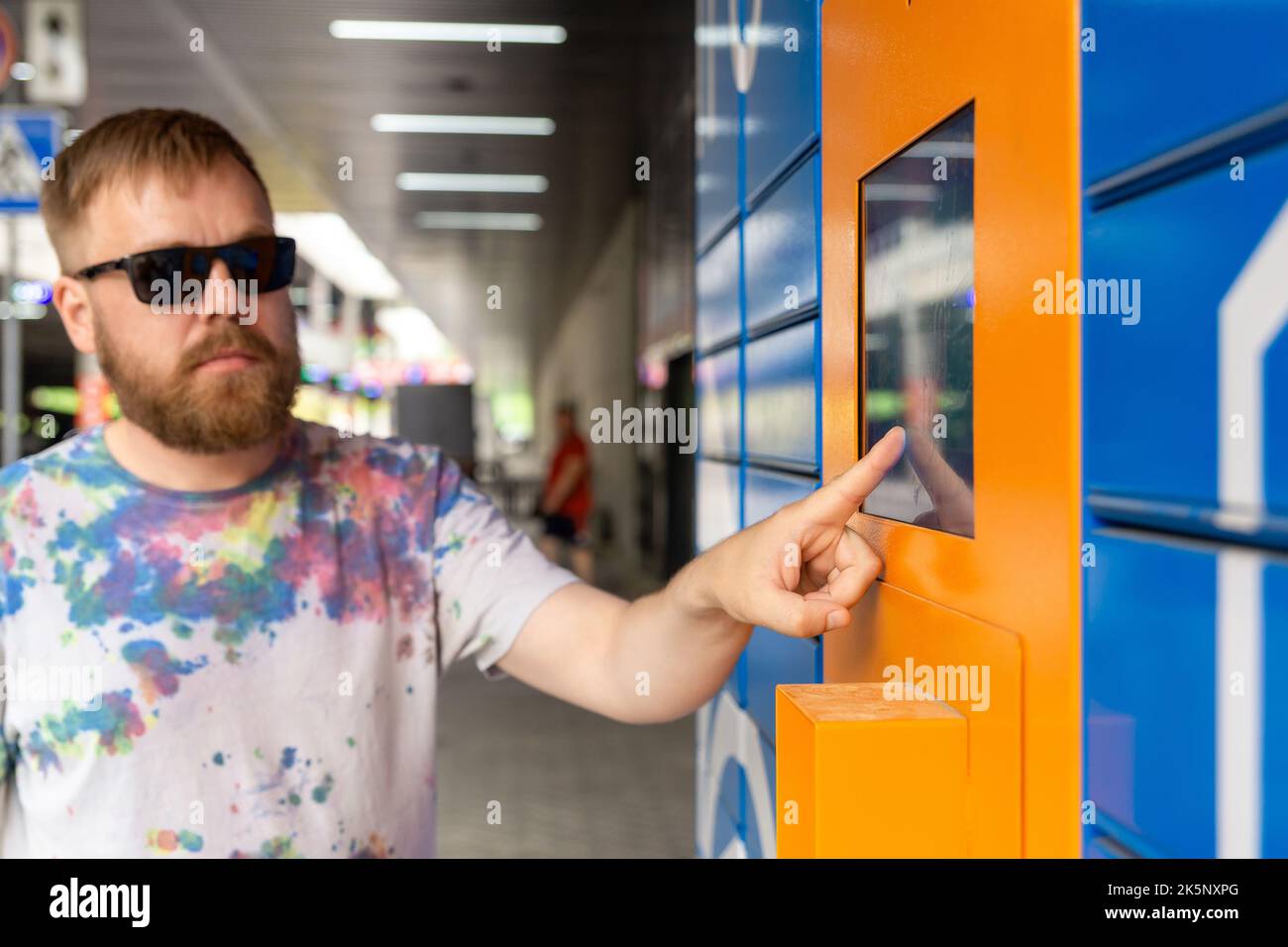 Man enters parcel code on screen and picks up parcel from automated ...