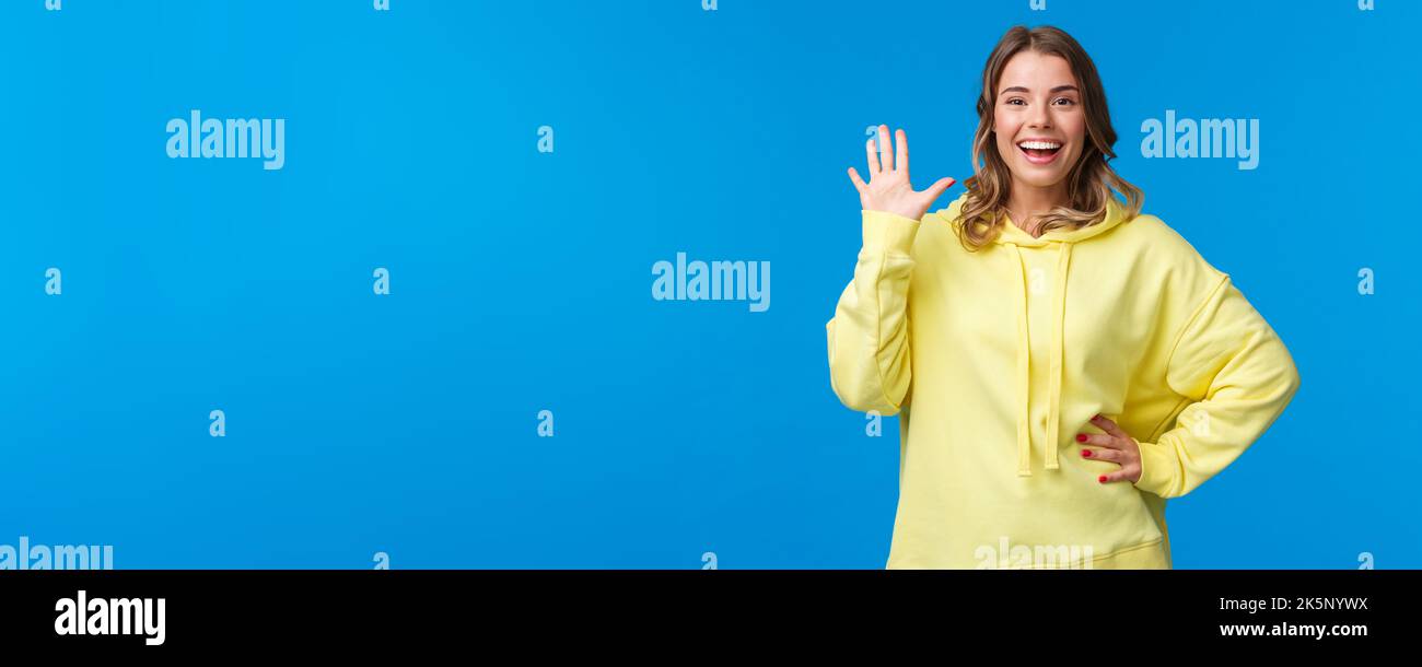 Cheerful friendly outgoing blond girl waving hand, informal greeting ...