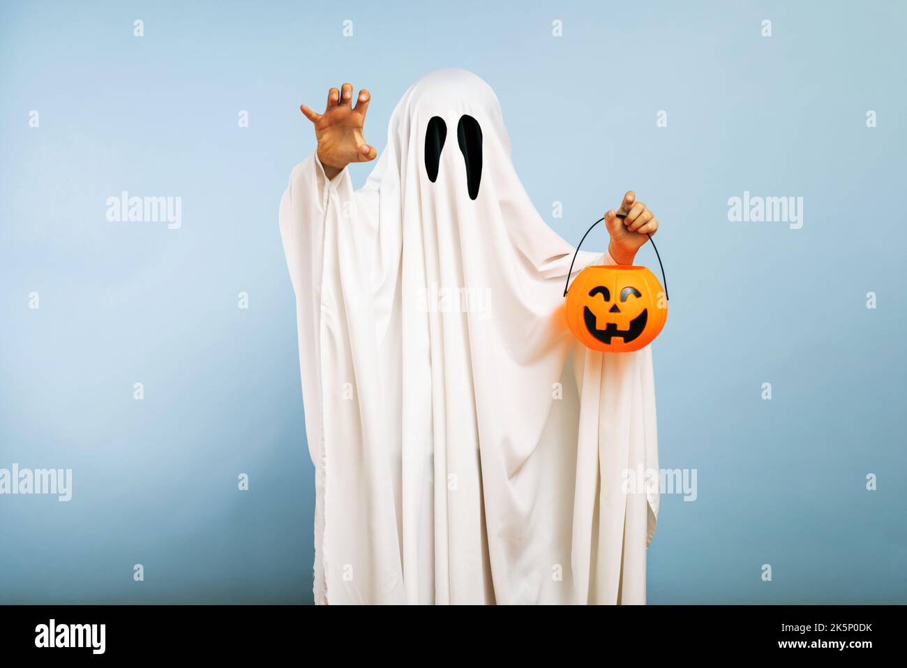 Child dressed up in white costume of scary ghost with pumpkin basket ...