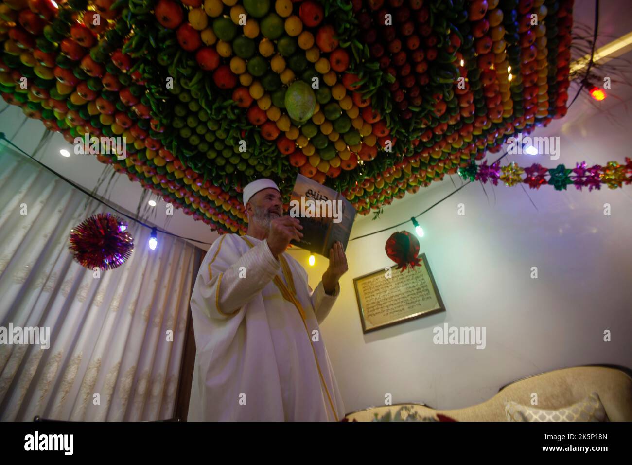 A Samaritan priest reading a book under the traditional ritual hut ...