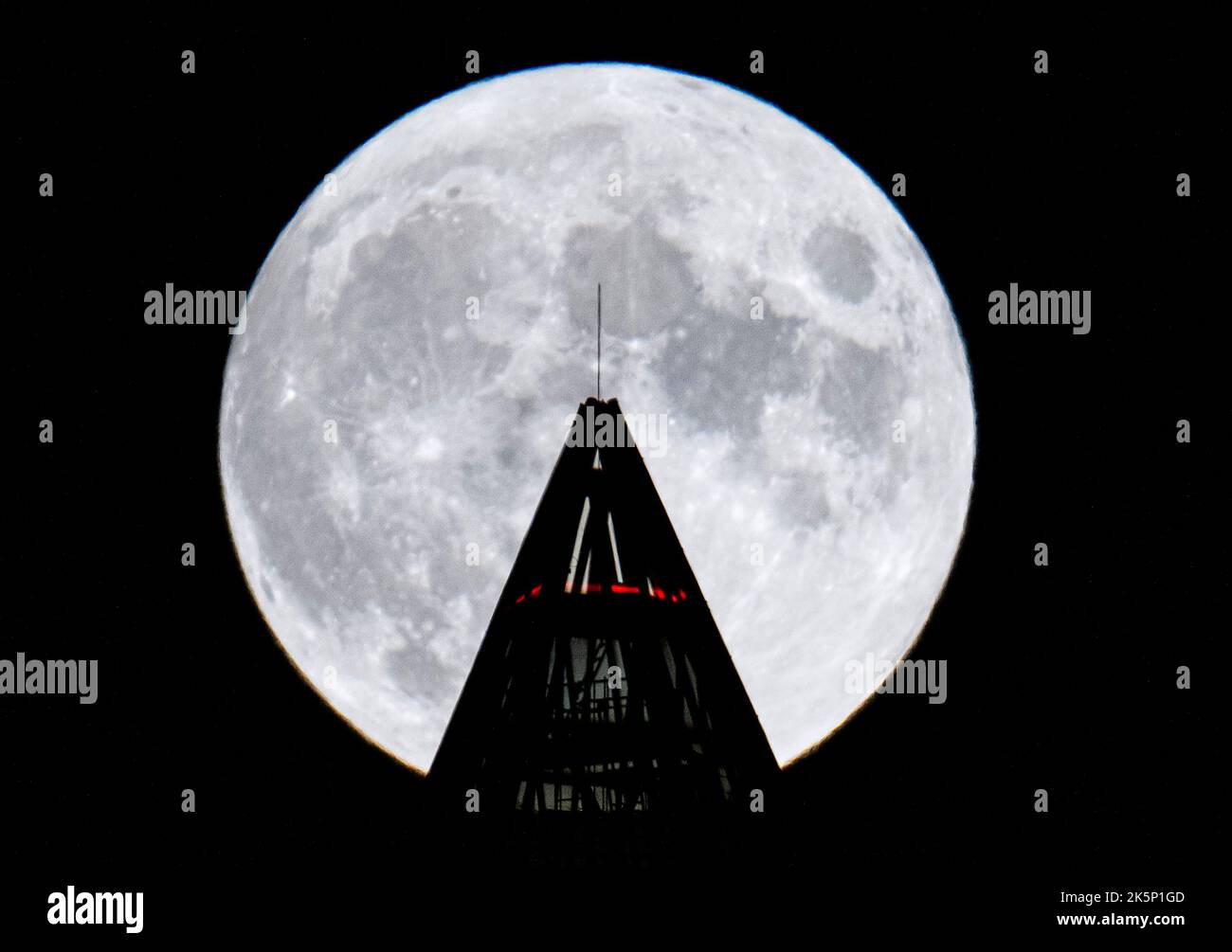 09 October 2022, Hesse, Frankfurt/Main: The full moon is above the top ...