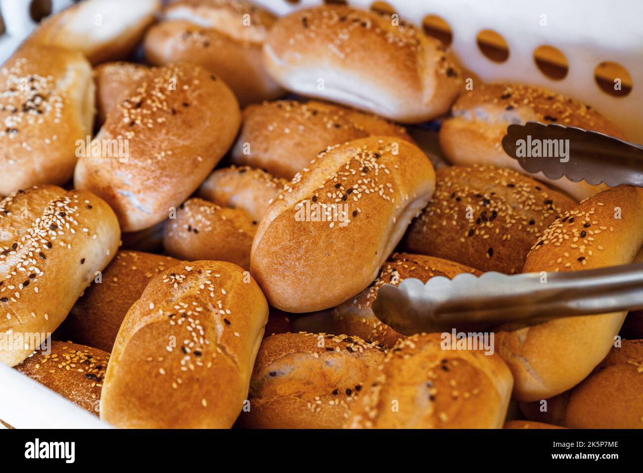 Many freshly baked bun in plastic box with pliers, close up, bakery ...