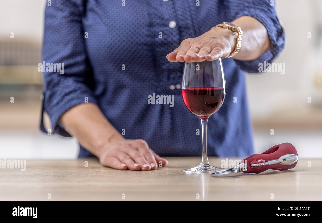 Detail of a female hand holding palm over a glass of red wine as a sign ...
