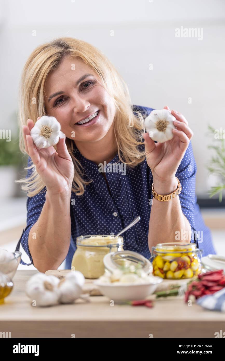 Happy woman takes garlic heads and makes them into preserves in the ...