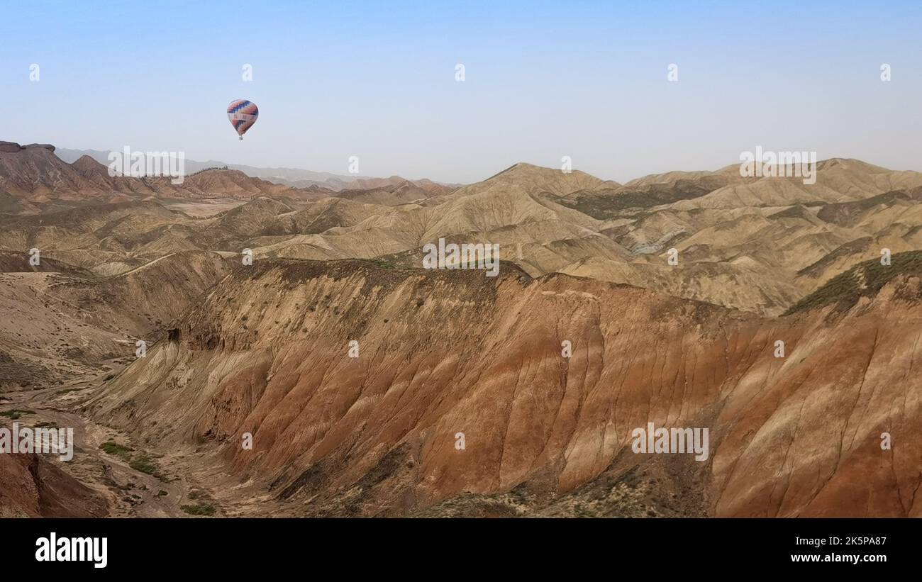A hot air balloon flying over rocky mountains Stock Photo - Alamy