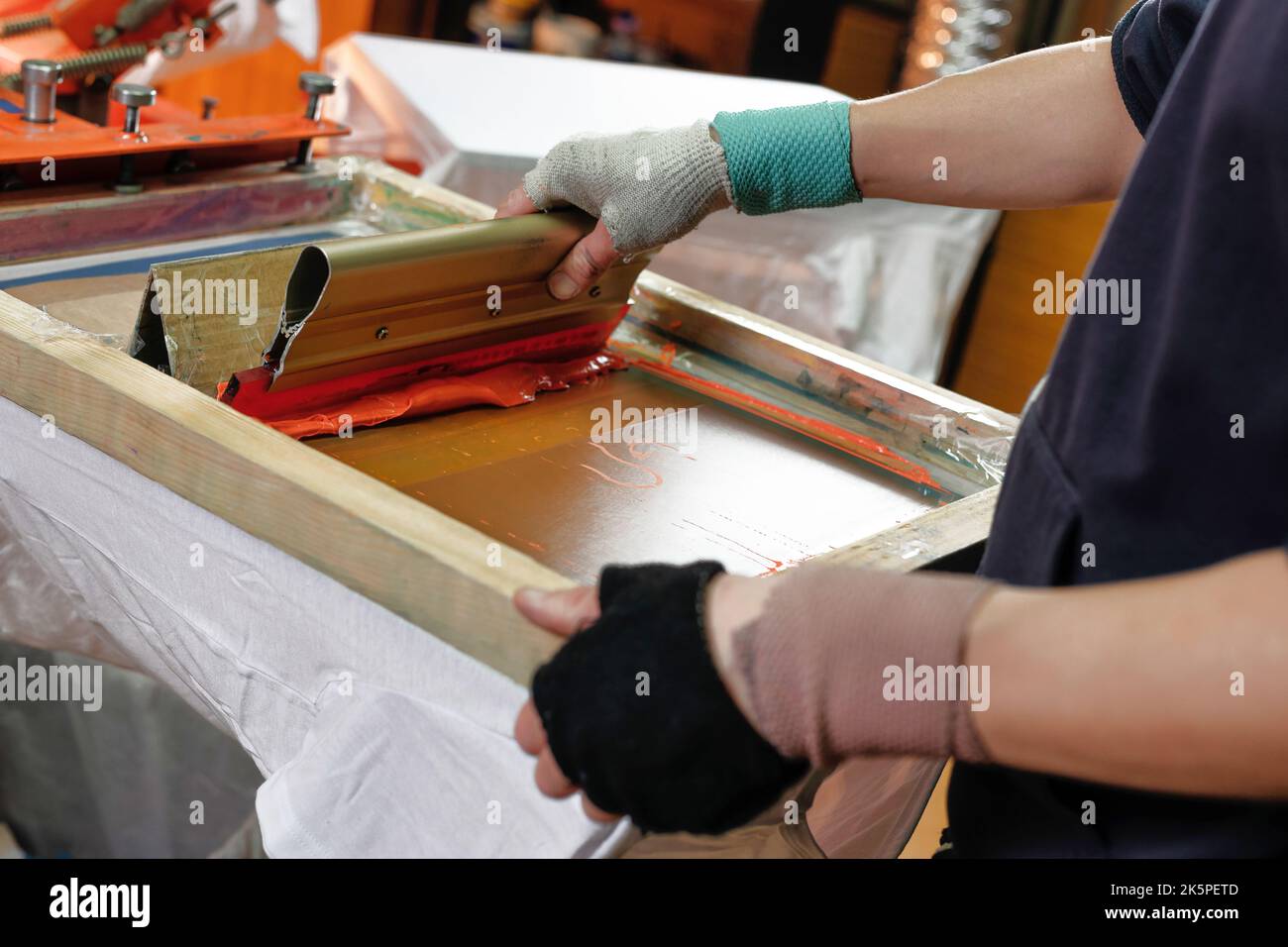 silk screen printing. male hand with a squeegee. serigraphy production ...