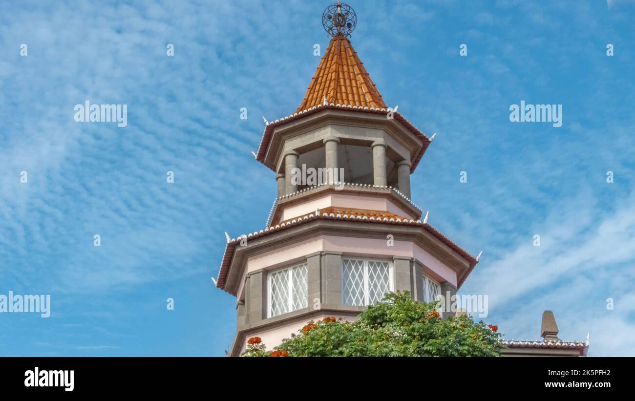 Octagonal tower building against a blue sky with a unique round metal ...