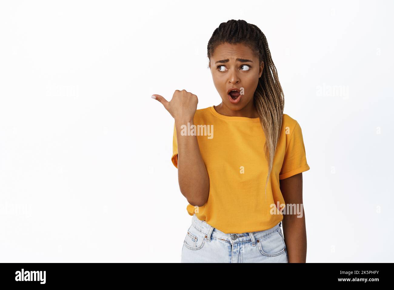 Shocked african american young woman pointing, looking left with ...