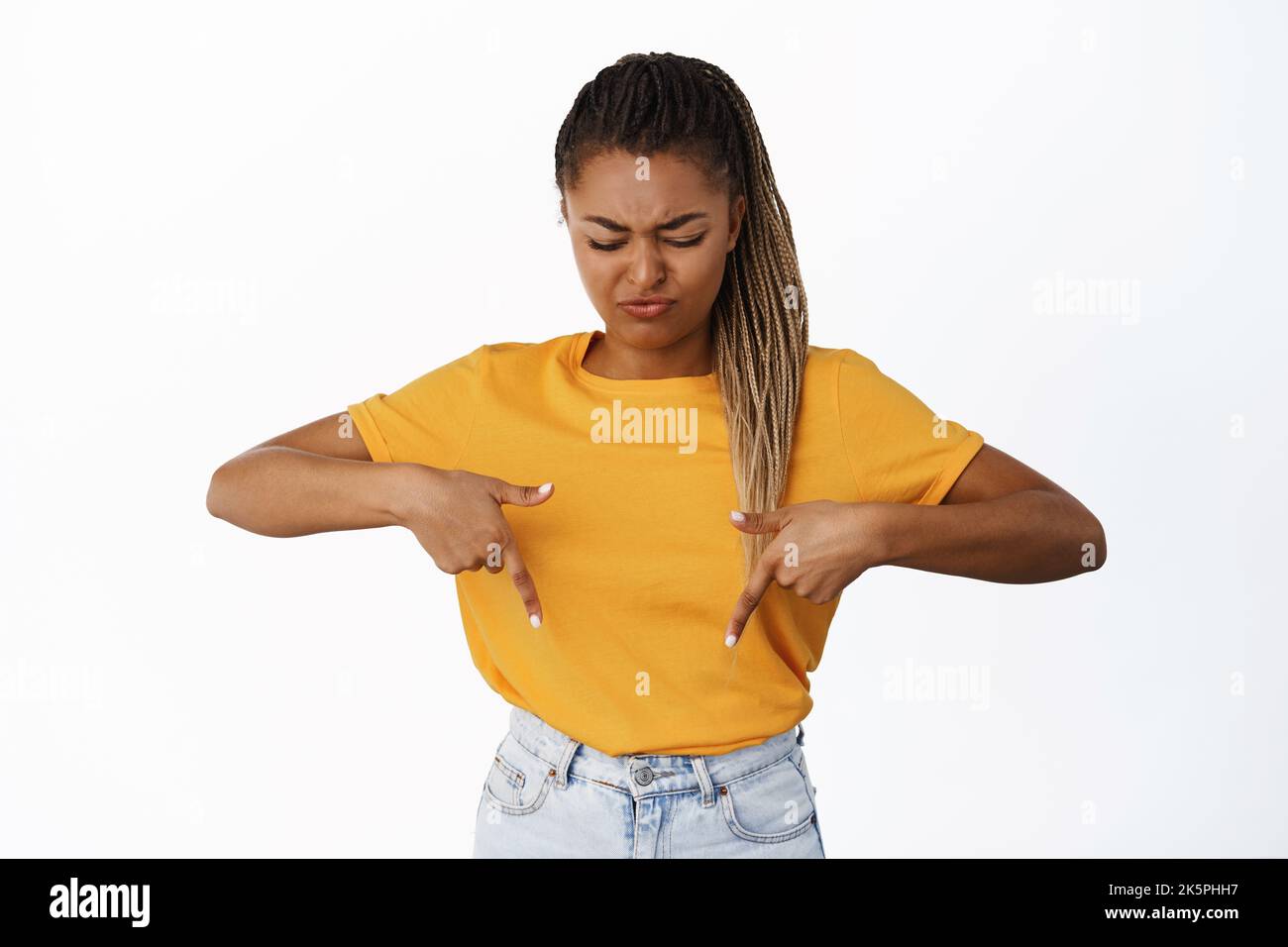 Dislike. Reluctant young Black woman pointing and looking down with ...
