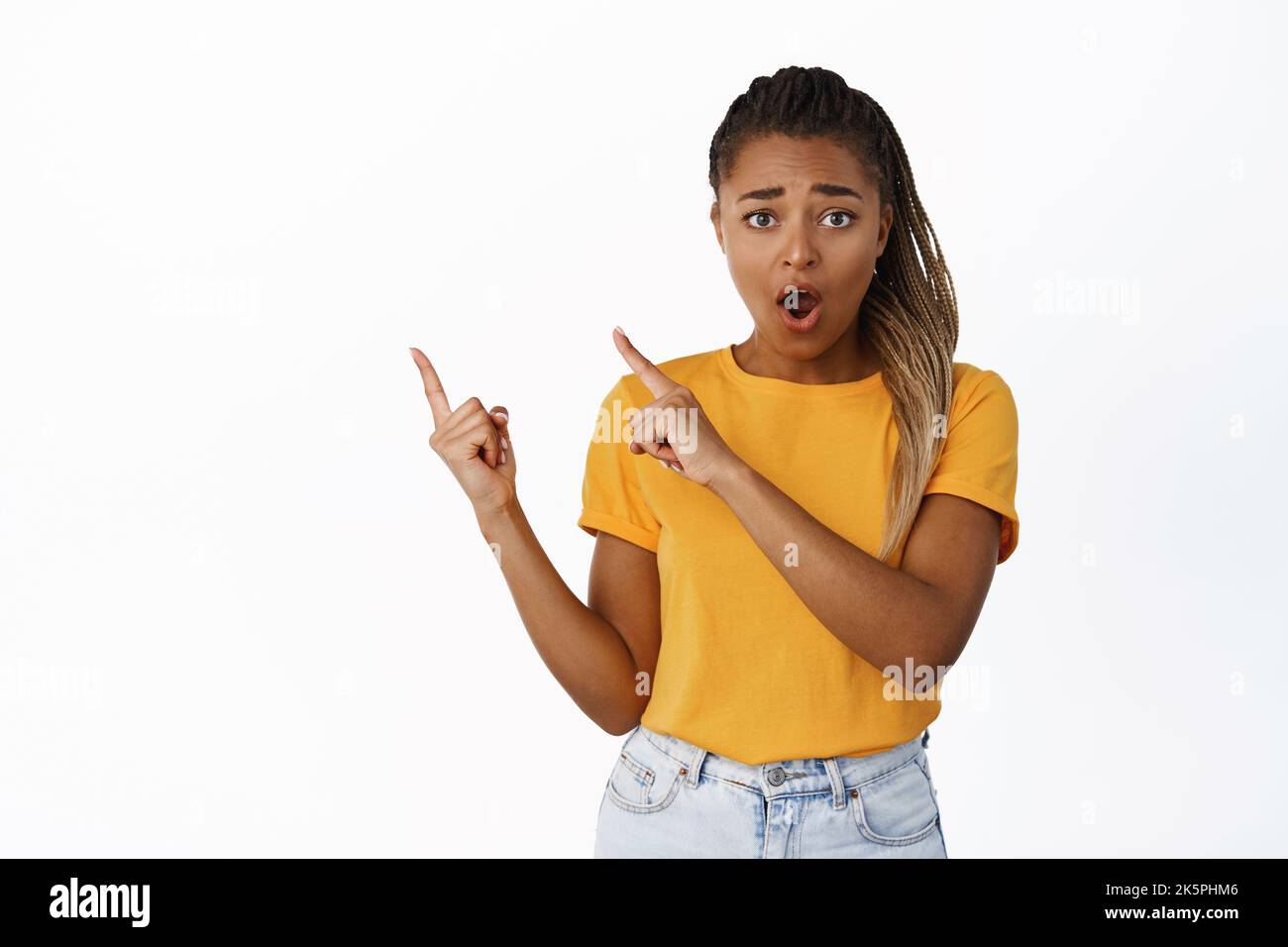 Surprised african american woman pointing fingers at upper left corner ...