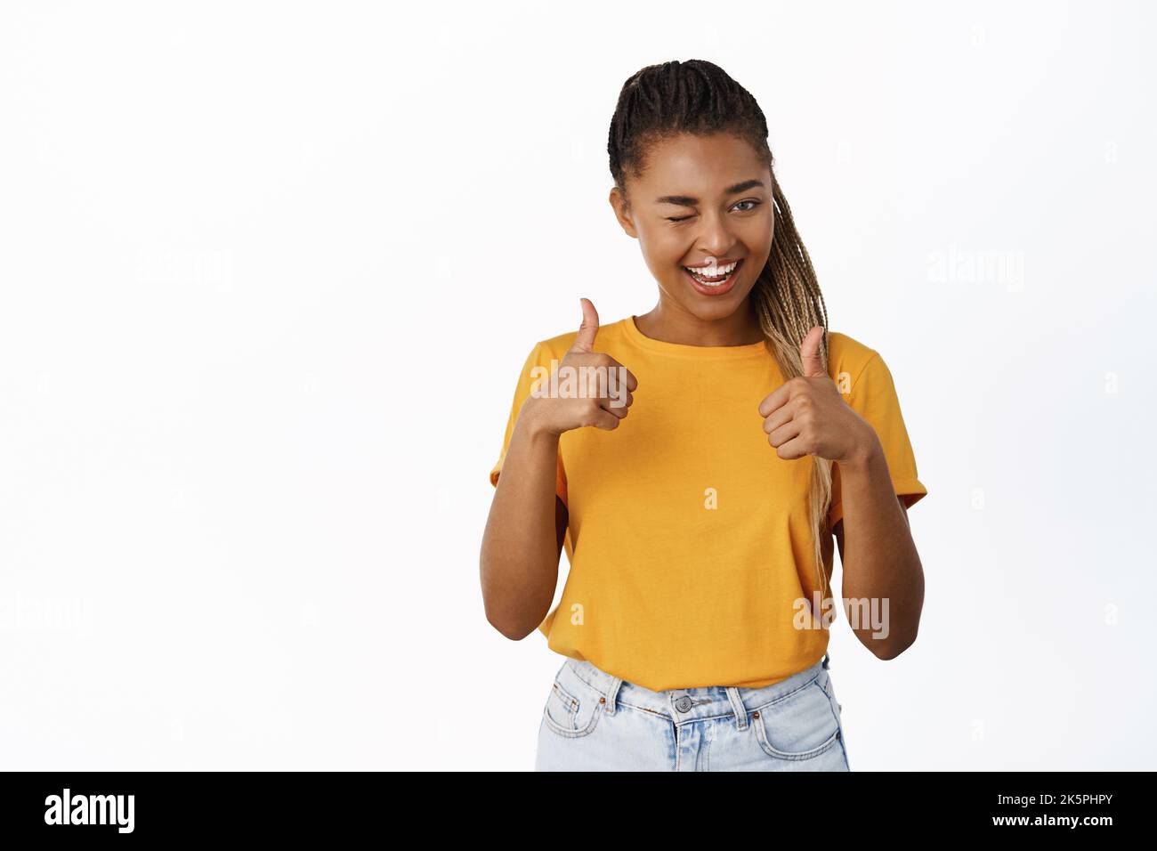 Portrait of beautiful young black woman shows thumbs up, winks and ...