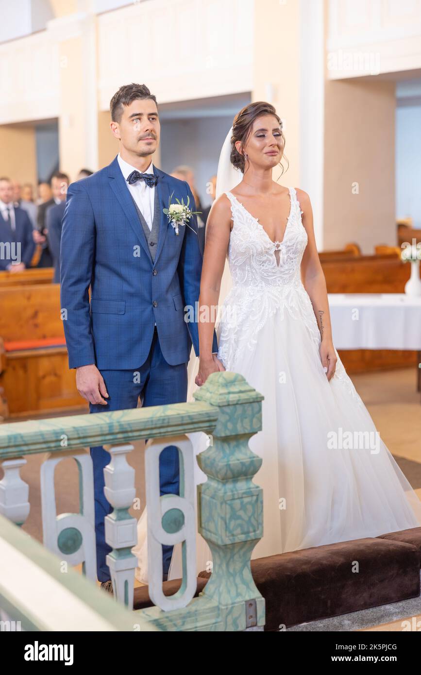 Christian bride and groom stand in front of the altar in the church ...