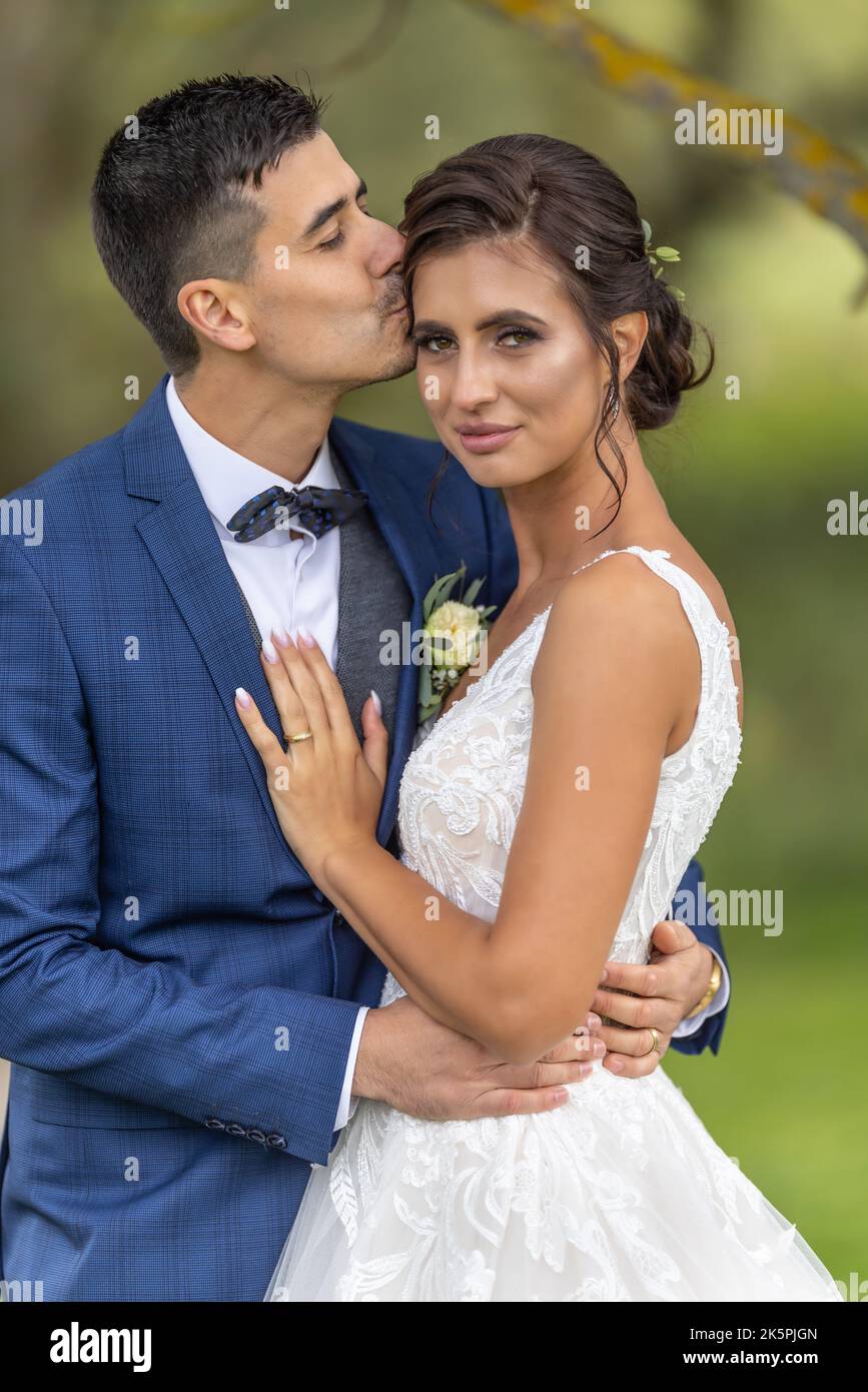 Happy husband kisses his beautiful wife on head during a just married ...