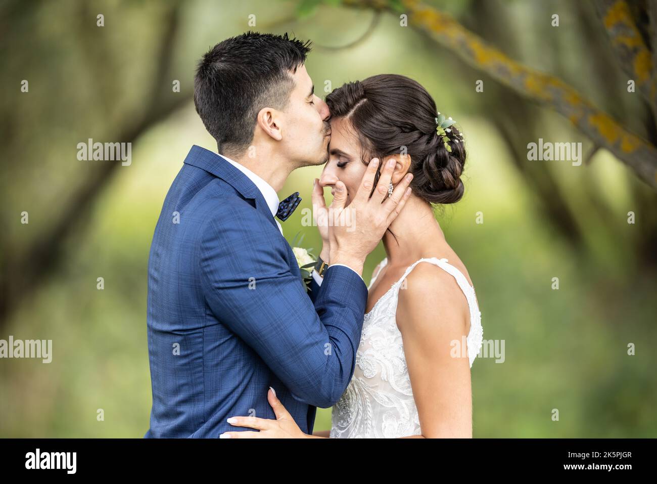 Freshly married husband holds his wife's head in his palms and kisses ...
