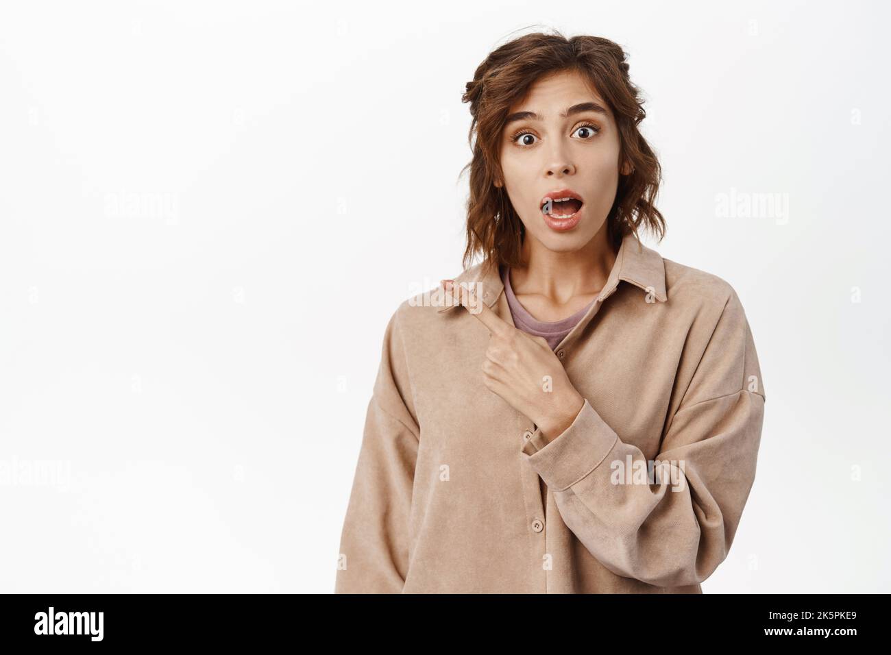 Directions. Portrait of excited brunette girl pointing left, showing ...