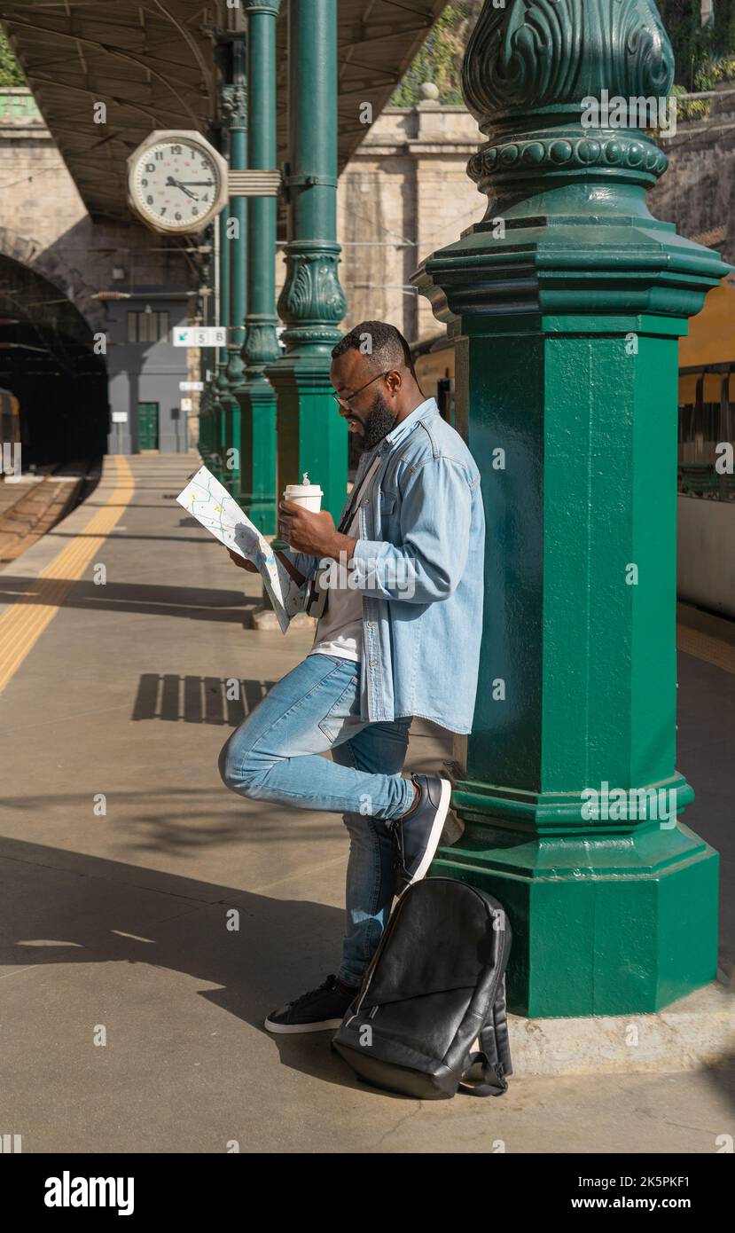 Happy young man with map and coffee at terminal train station Stock ...
