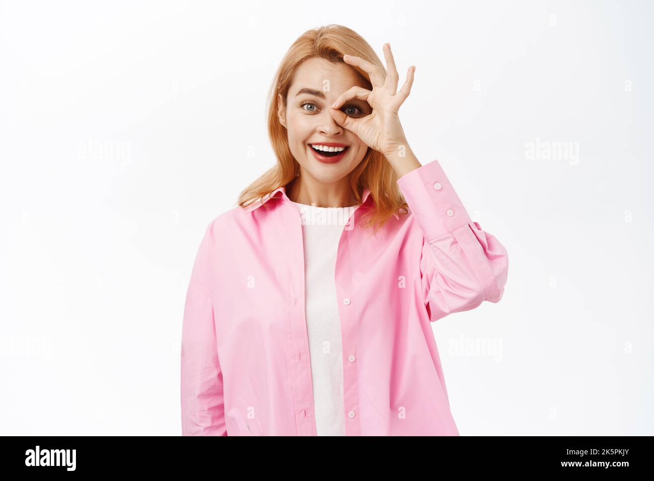 Portrait of happy smiling woman showing okay, ok sign over eye, approve ...