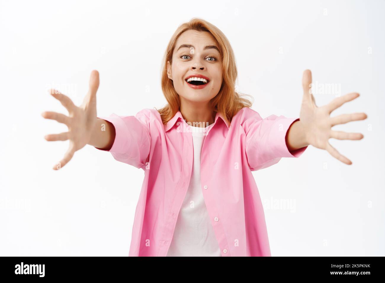 Image of happy young woman reaching her arms for something, grabbing ...