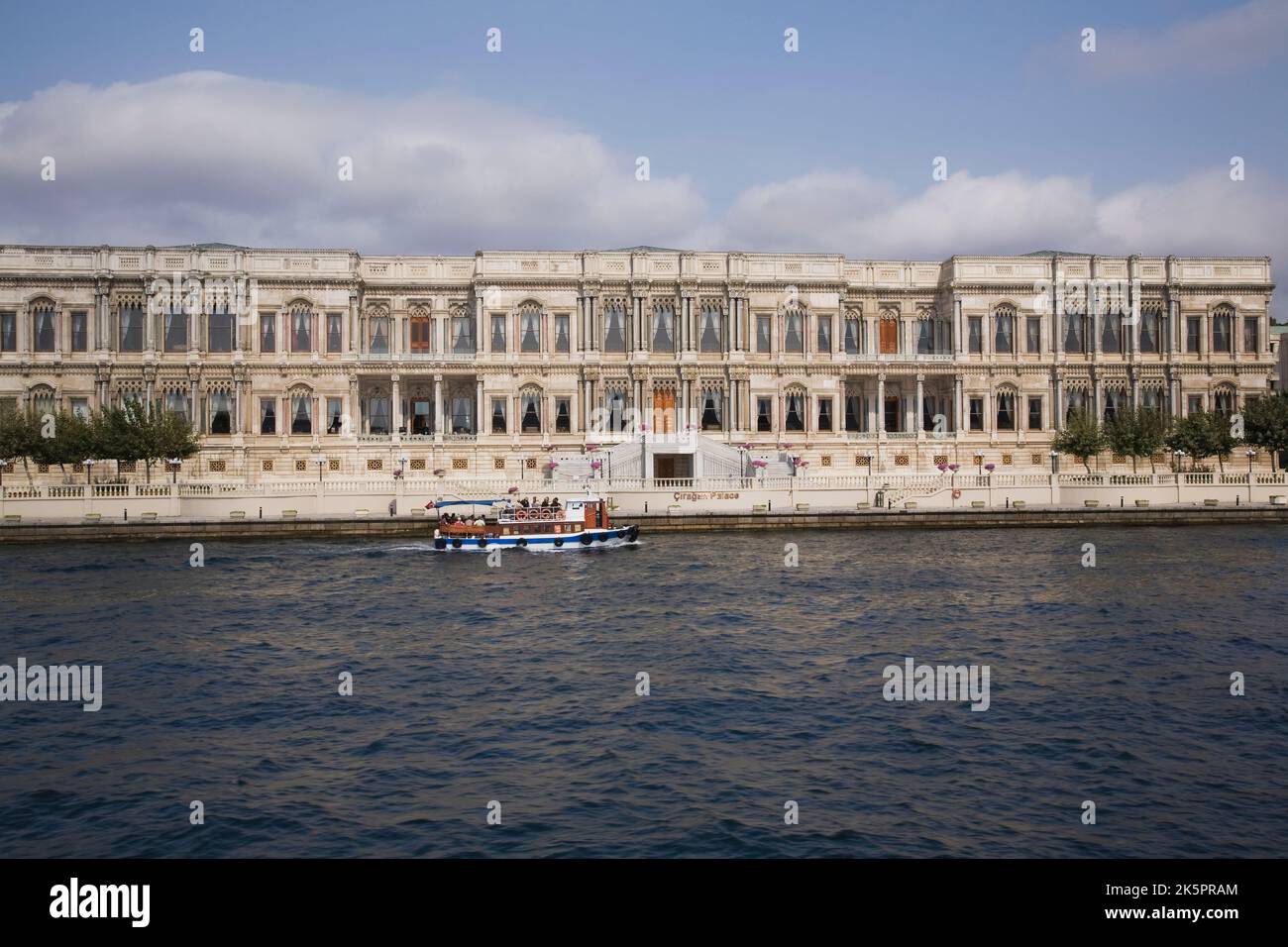Tour boat on the Bosphorus strait passing in front of the Ciragan ...