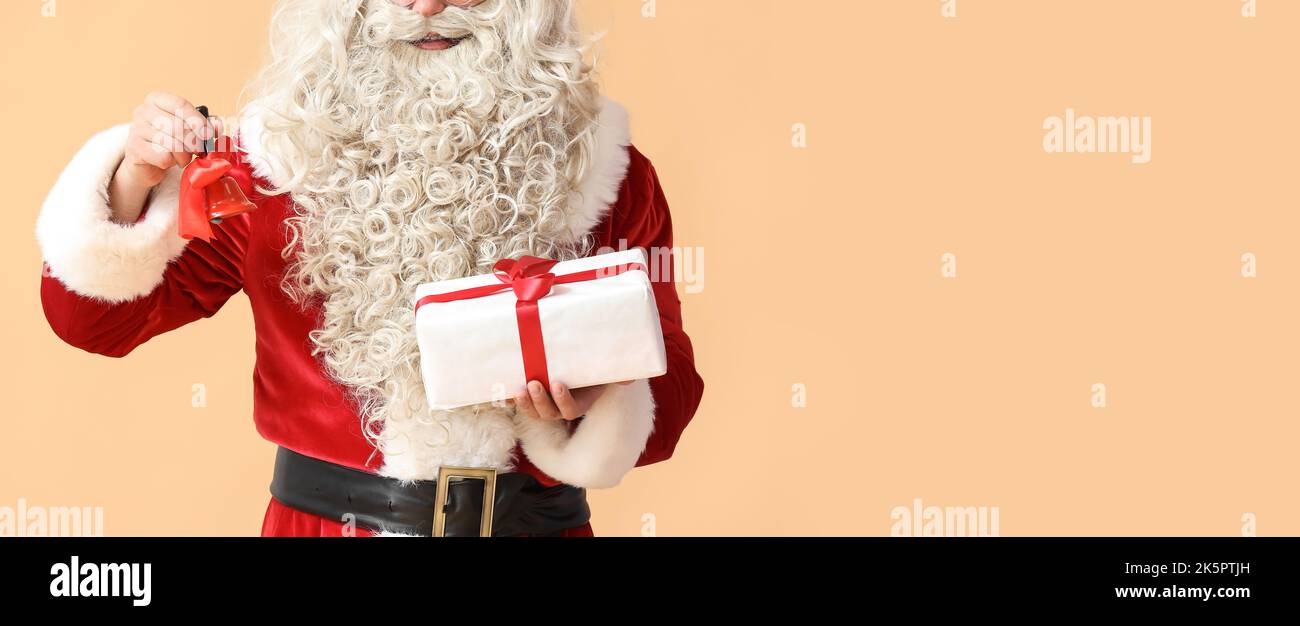 Santa Claus holding Christmas bell and present on beige background with ...