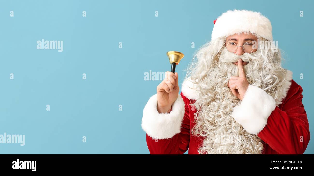 Santa Claus with Christmas bell showing silence gesture on light blue ...