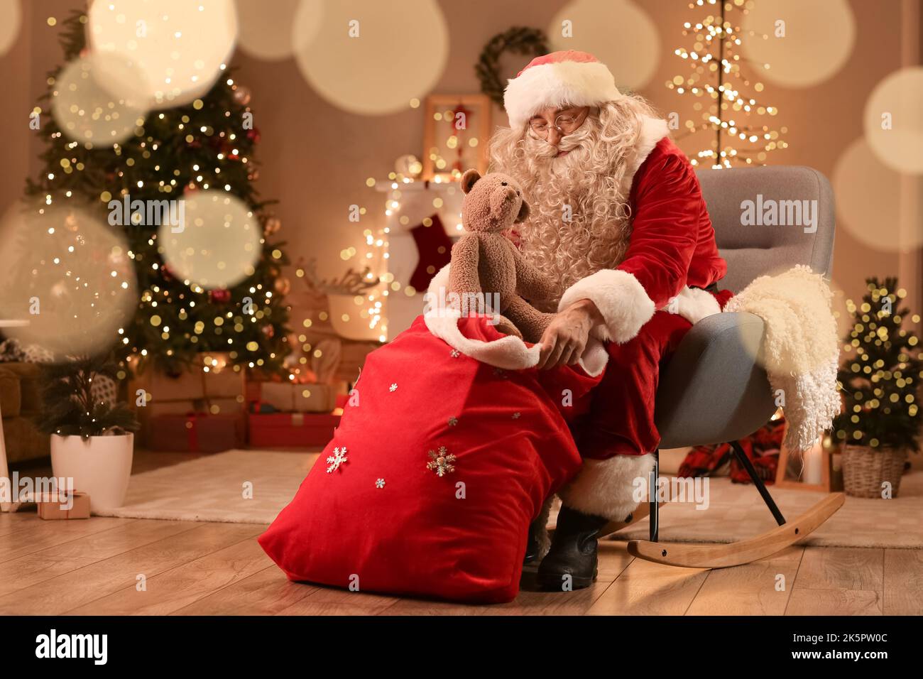 Santa Claus taking teddy bear from sack bag in room on Christmas eve ...