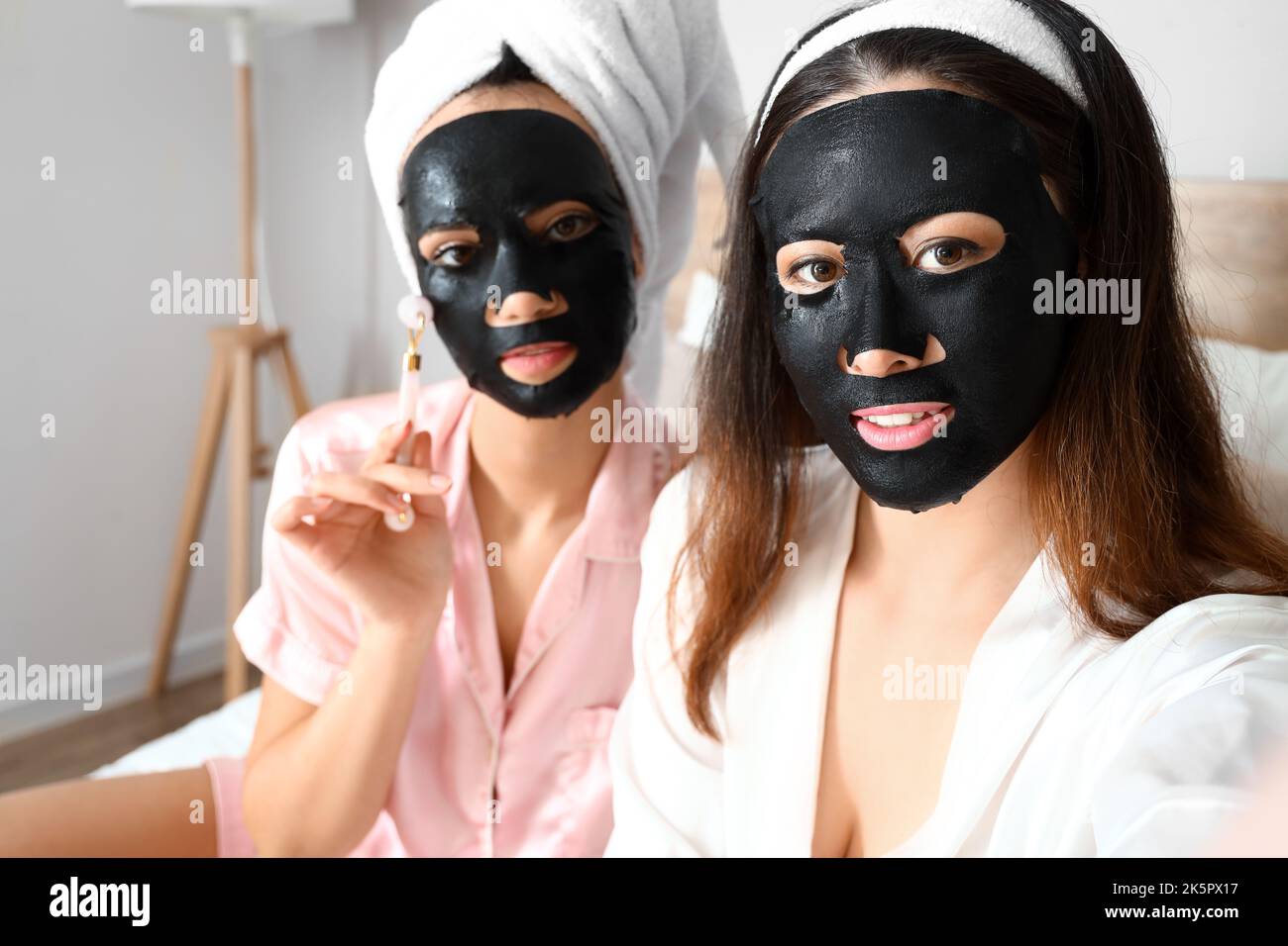 Beautiful young women with activated charcoal sheet facial masks in ...